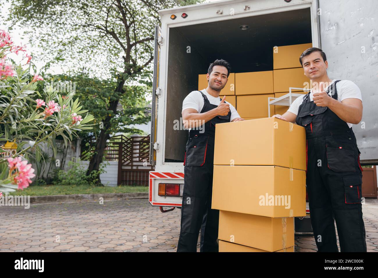 Employees work together unloading cardboard boxes from the truck for a ...