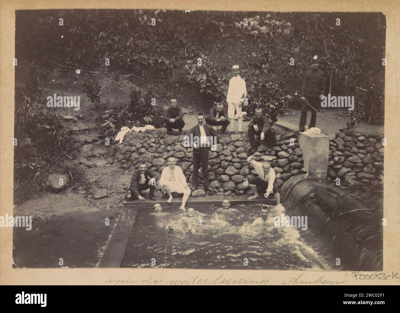 Swimmers and men at a dam and a basin of the water pipeline on Ambon ...