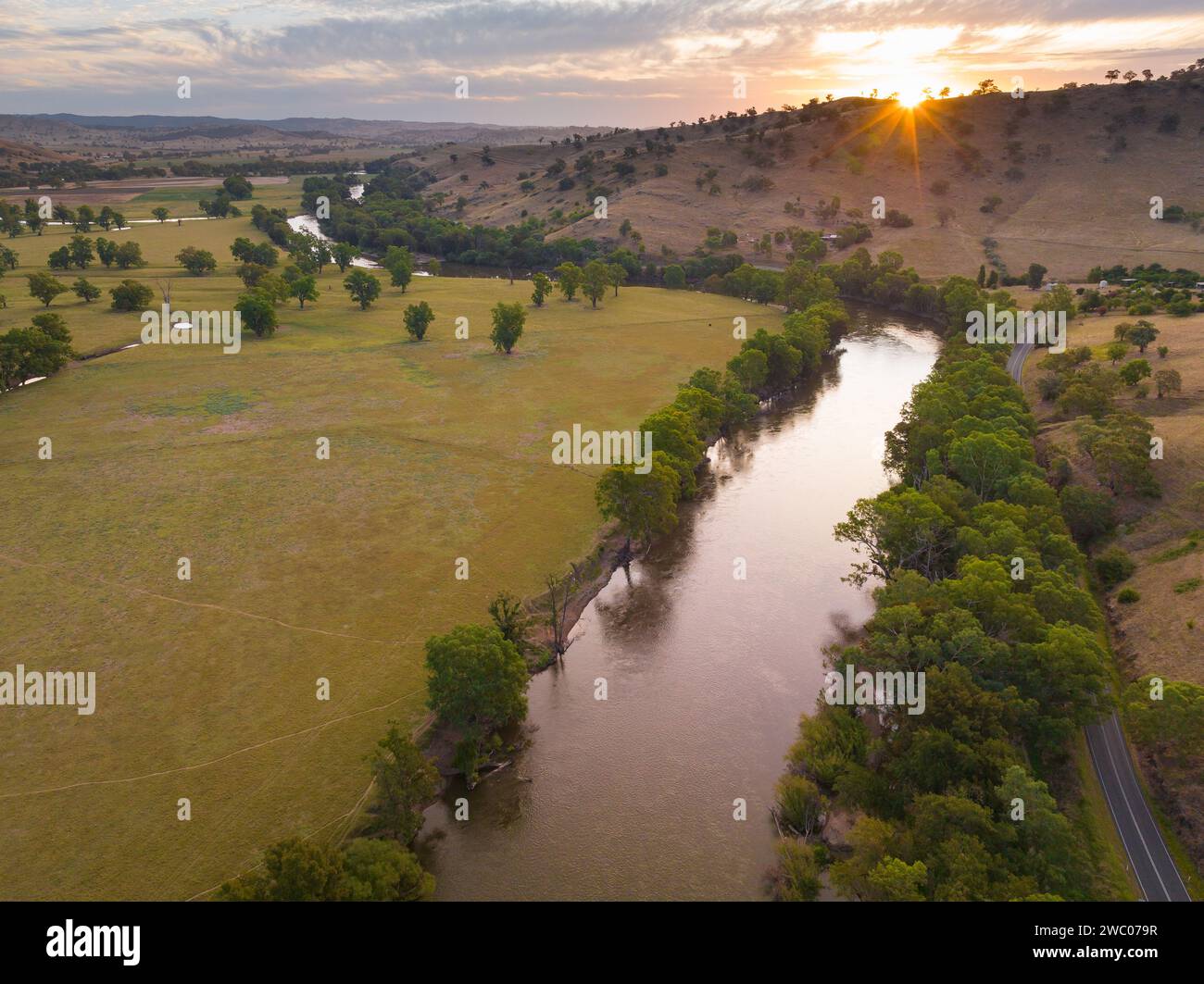Aerial view of sunset over hills surrounding a river flowing through ...