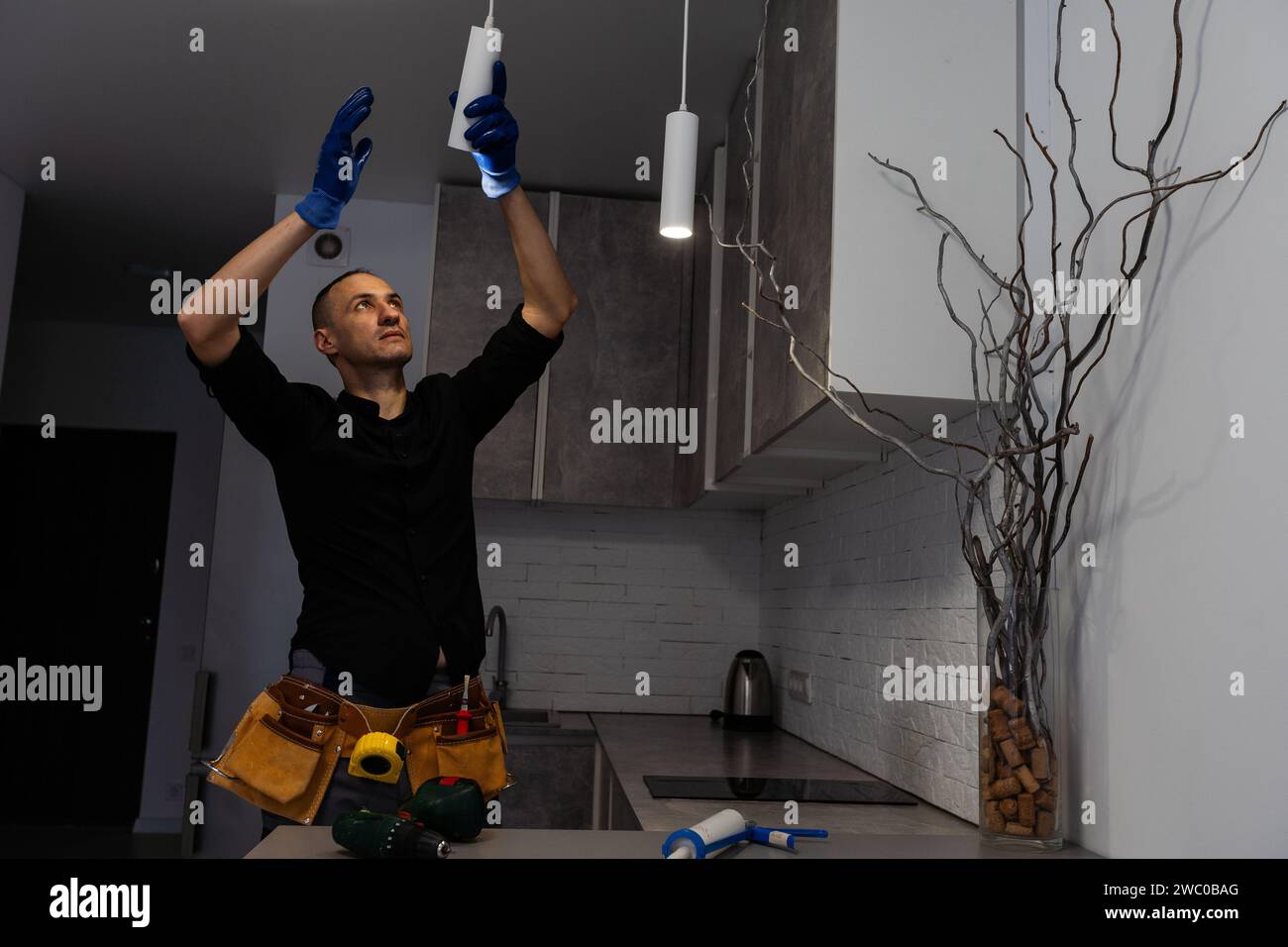 Worker repairing lamp on stretch ceiling indoors Stock Photo - Alamy