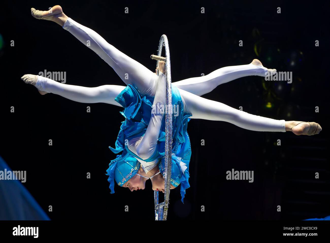 Two acrobat girls show a circus number on a dark background. Acrobatic ...
