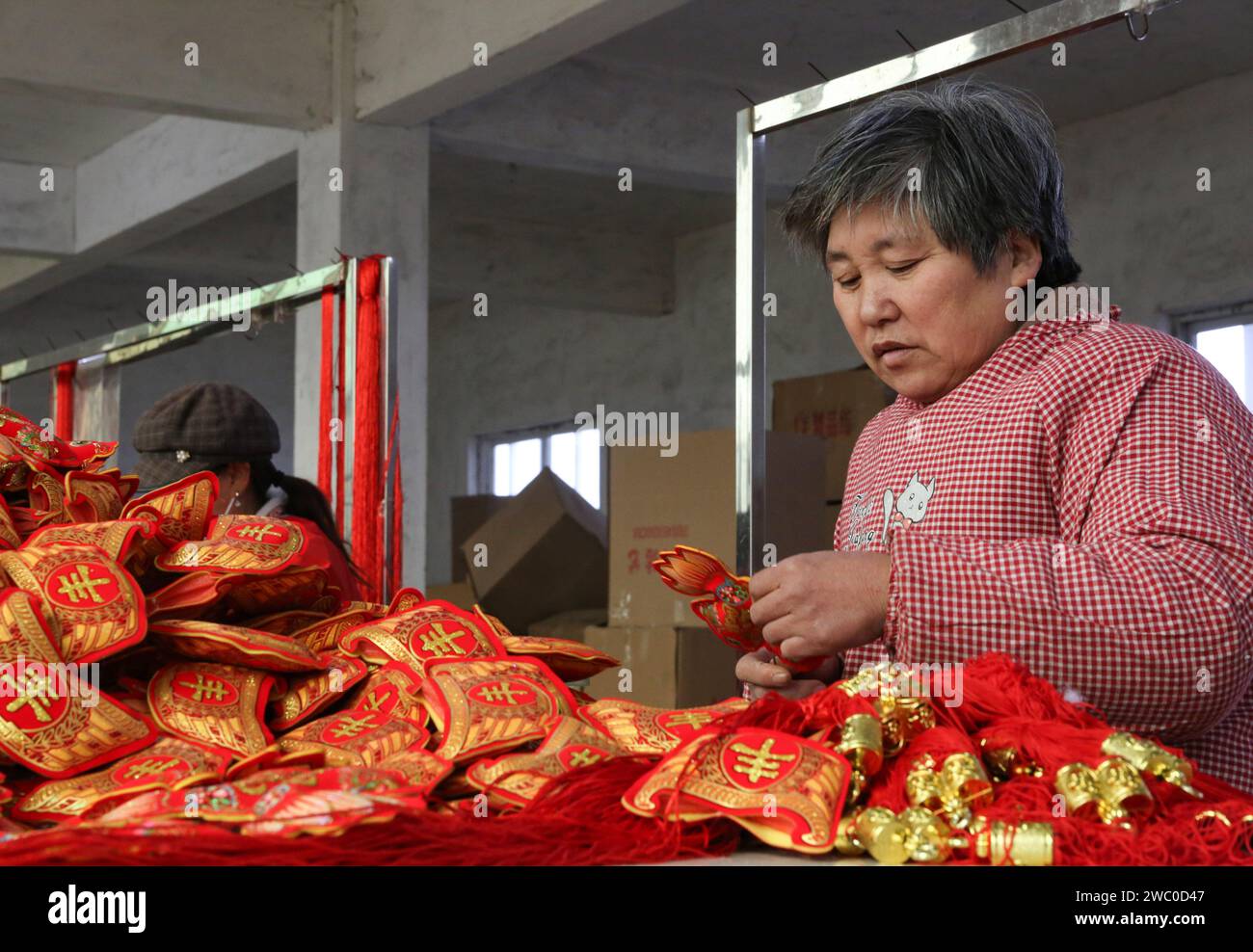 Linyi, China. 13th Jan, 2024. A staff member is making a ''Chinese knot ...