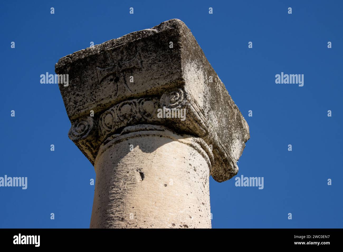 An ancient stone column set against a blue cloudless sky in the old ...