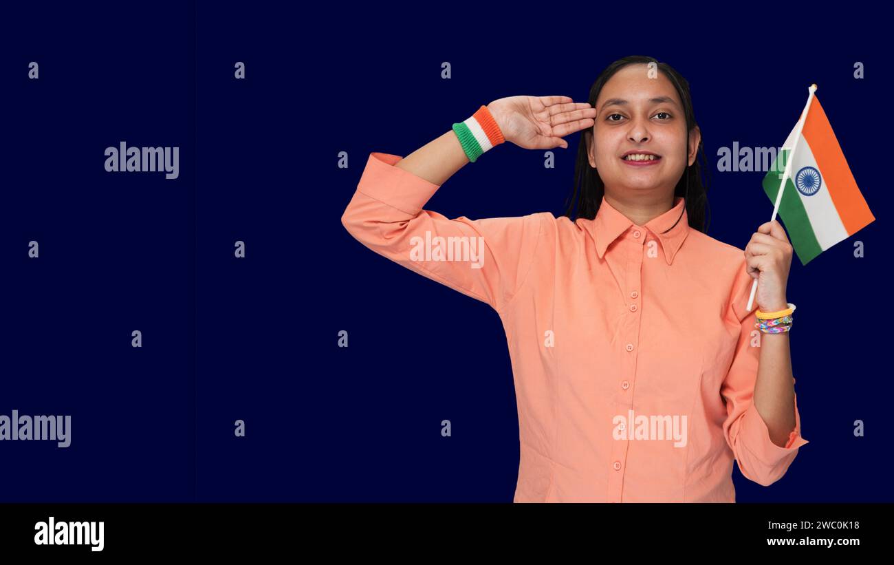 A young Indian girl salutes to national flag, holding the national flag ...