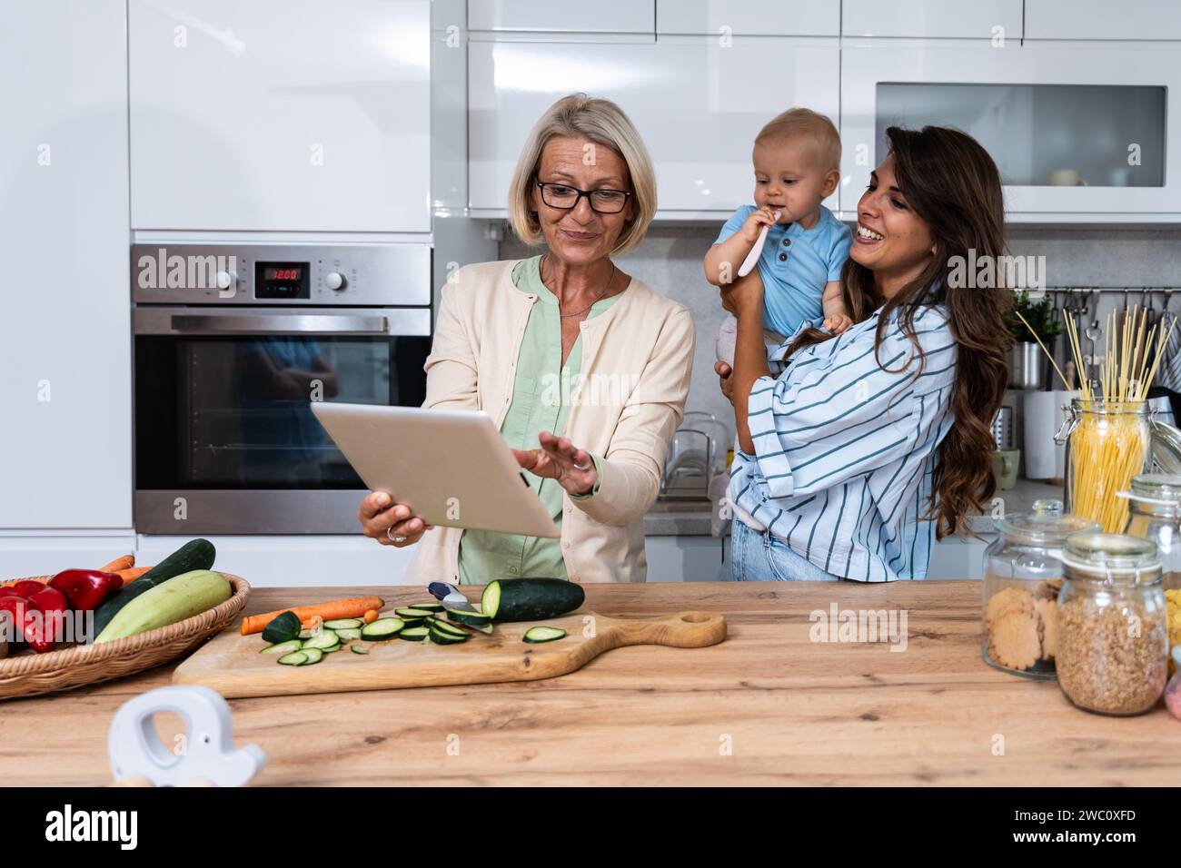 Three Generations Family. Grandma, mother and baby record a cooking ...