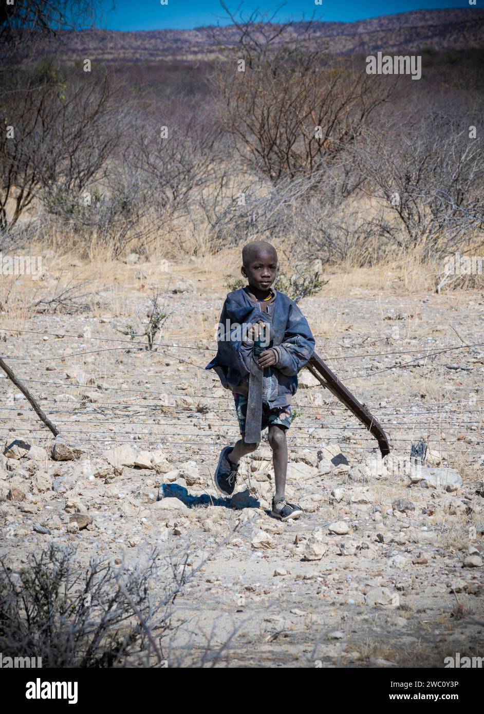 A young shepherd boy carries a large machete in a case for protection ...
