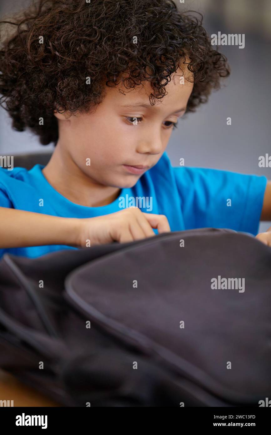 Boy, education and school bag in a classroom, student and searching ...