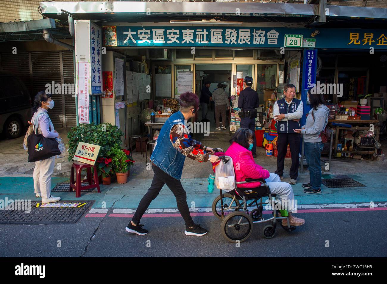 Taipei. 13th Jan, 2024. Couple with wheelchair exits polling station ...
