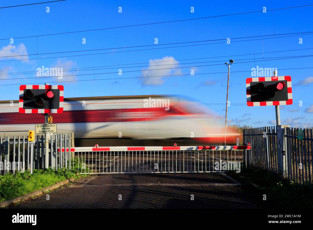 An Azuma train passing red lights at an unmanned Level crossing, East Coast Main Line Railway ...