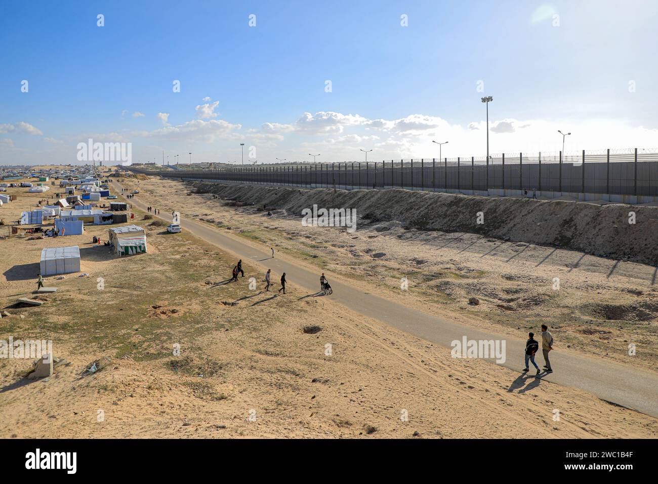 Gaza. 12th Jan, 2024. People walk on a road near the Gaza Strip's ...