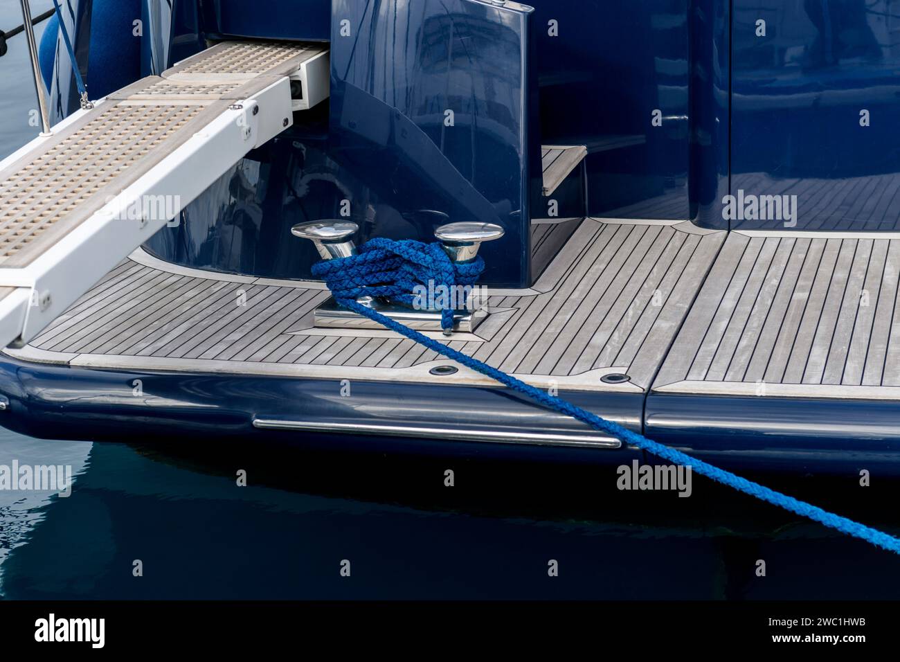 Stainless steel cleat with blue rope on a superyacht deck. Mooring line ...