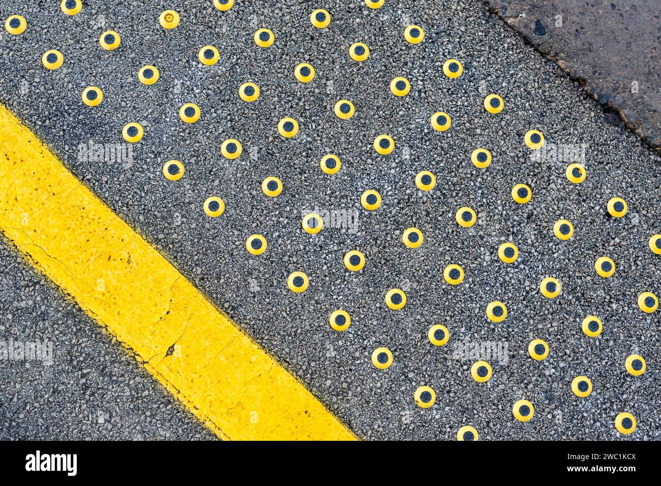 Tactile warning strip, yellow line with black and yellow studs at ...