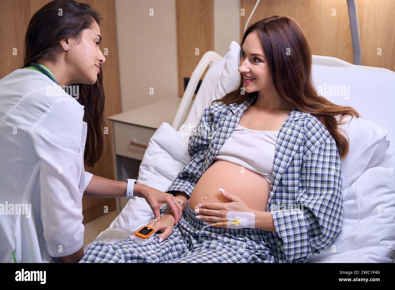 Female nurse measuring pulse with pulse oximeter of young pregnant ...