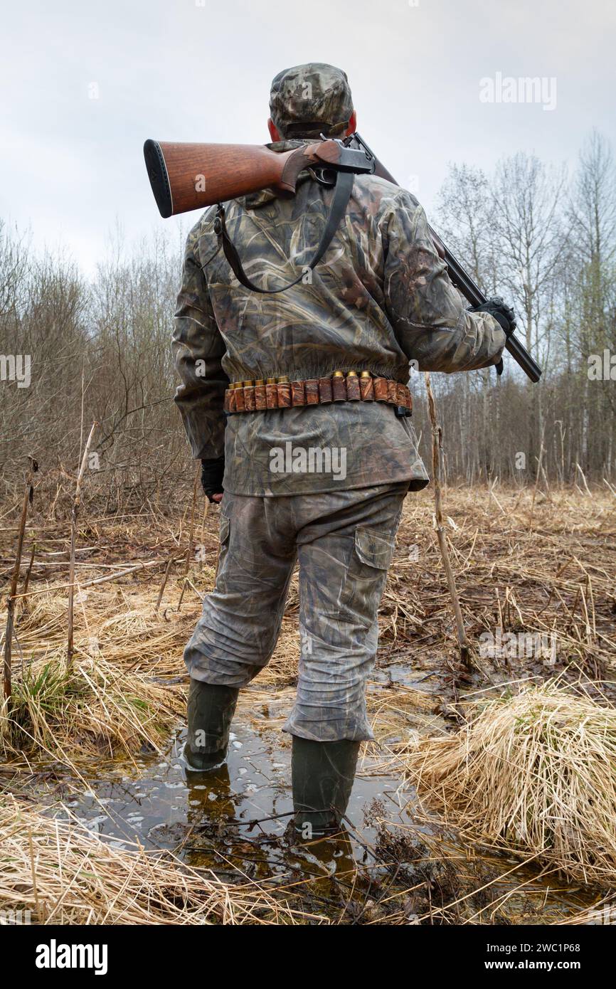 A hunter stands in a wet clearing in a spring forest. The evening ...
