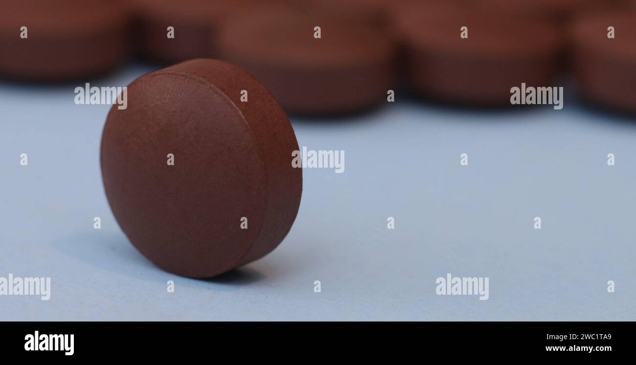 One brown pill against the background of many exactly the same pills ...