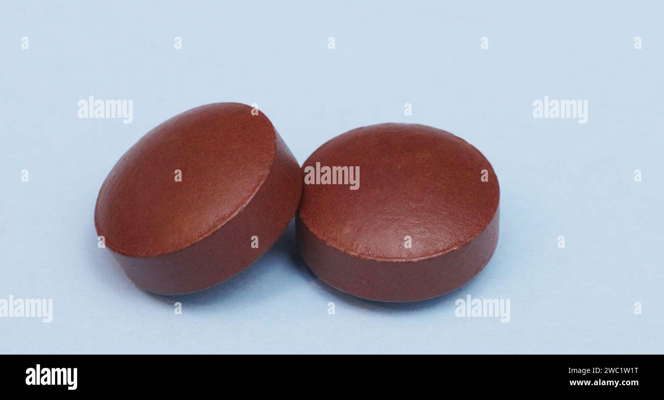 pharmaceutical concept. Two red-brown pills close-up on a light blue ...