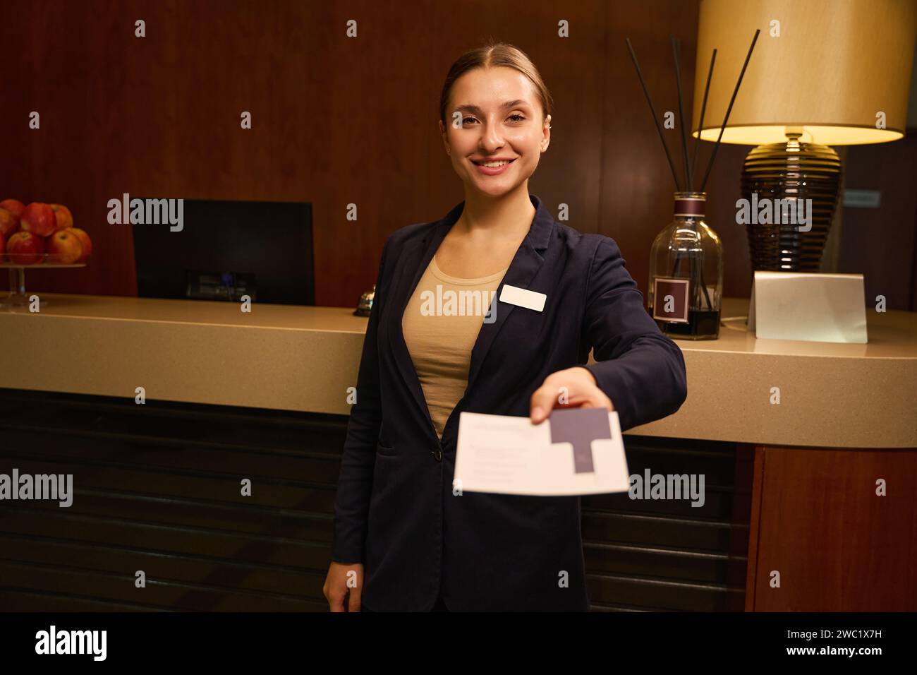Joyful woman receptionist standing and giving someone a keycard Stock ...