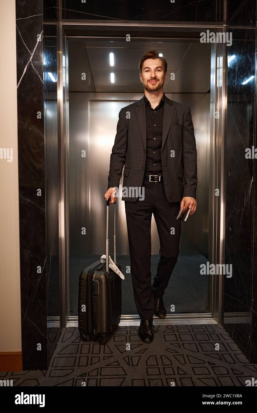 Happy guy with suitcase walking out elevator Stock Photo - Alamy