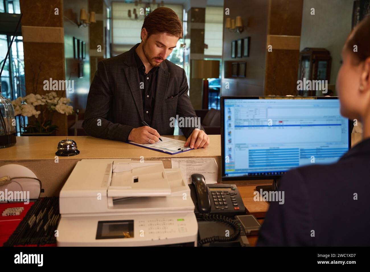 Male visitor filling registration form at reception desk Stock Photo ...