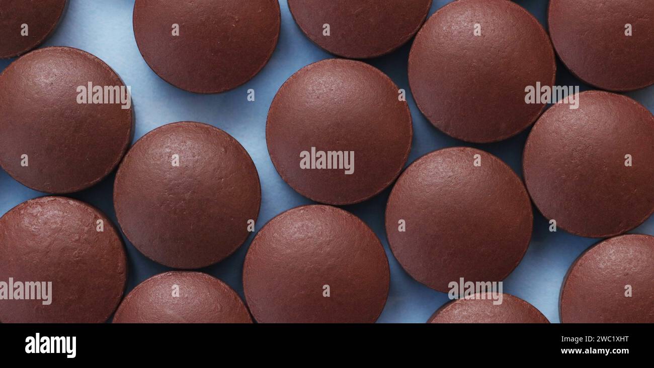Close-up brown pills on a paper background in blue. Herbal supplements ...