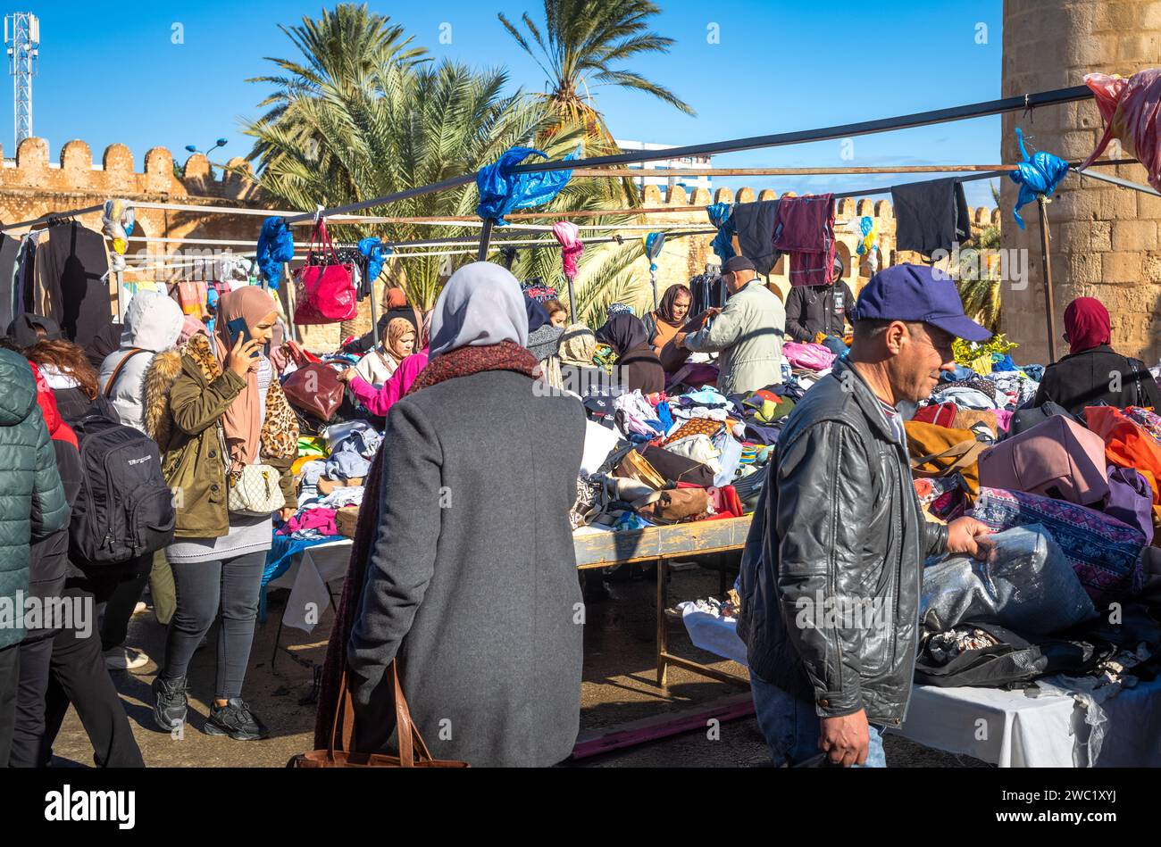People shopping at a busy traditional open air clothing market next to ...