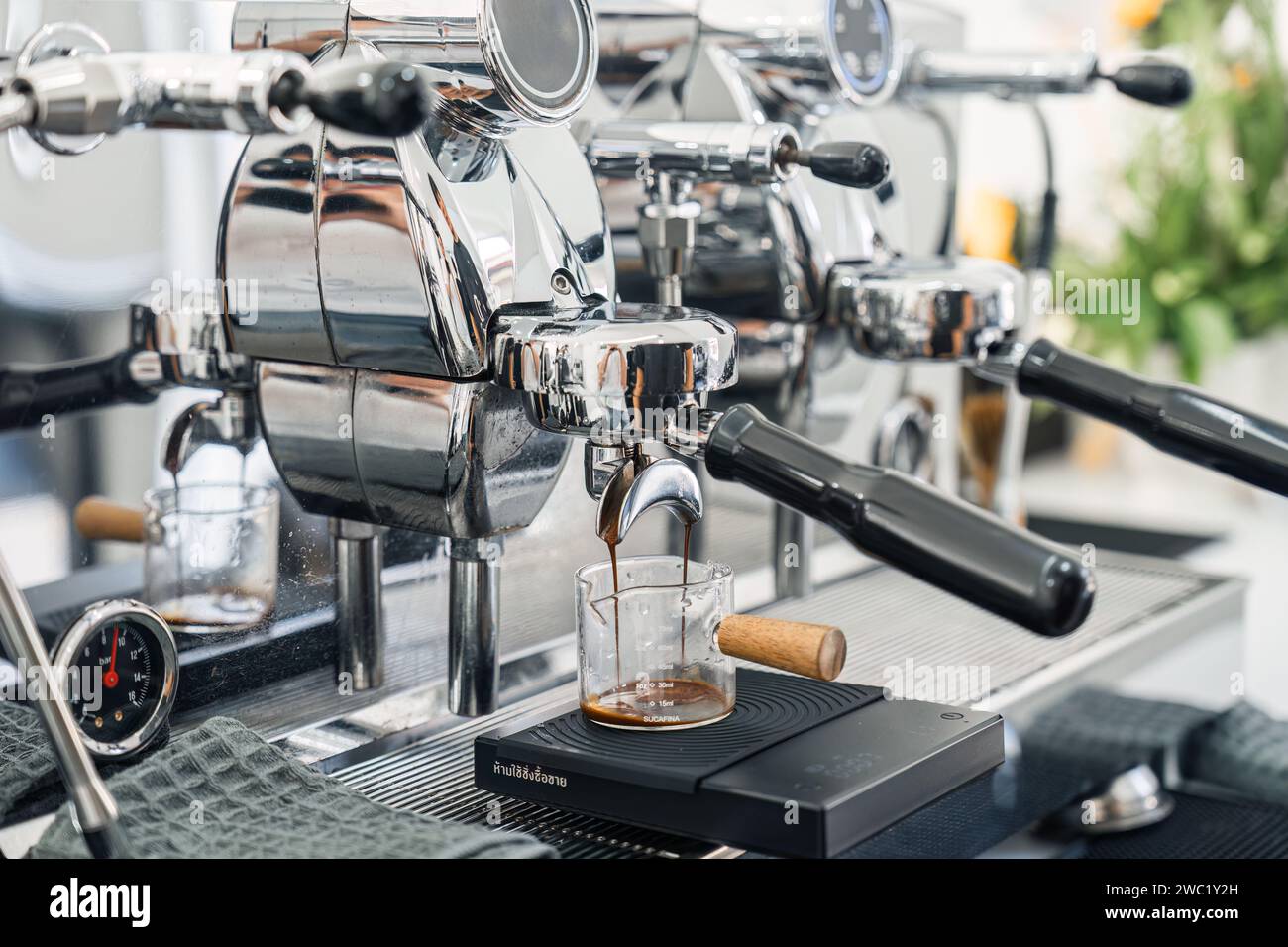 Metallic espresso machine making hot coffee into dosing cup on counter ...