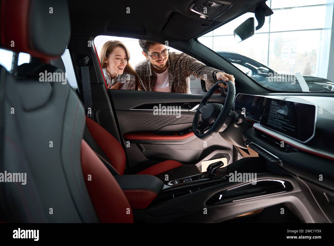 Woman with man look inside of car at dealership choosing suitable ...