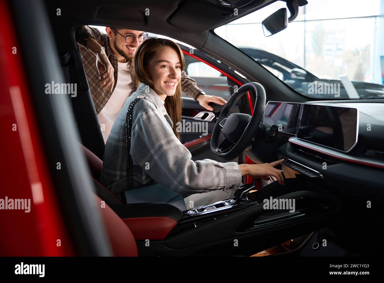 Woman and man choosing model of car in dealership testing model for ...