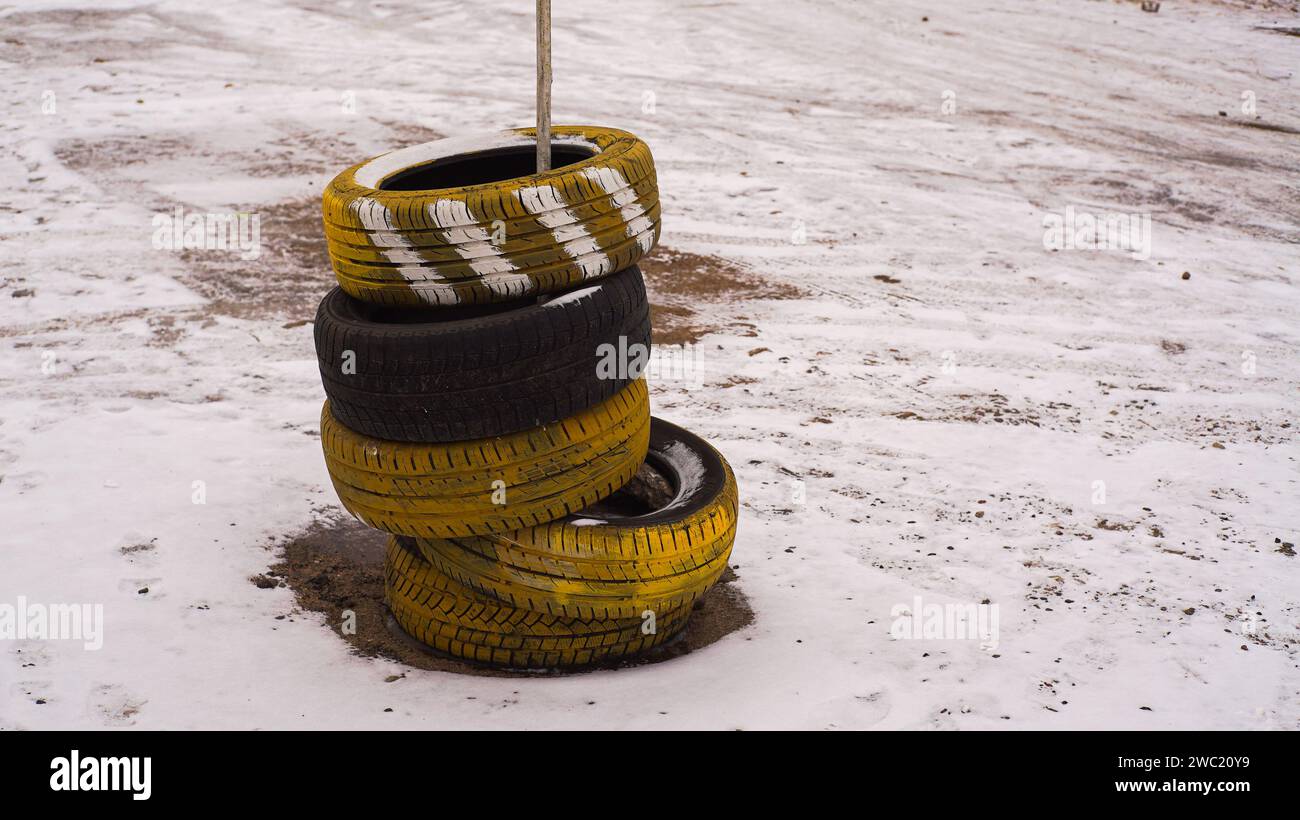 Old painted rubber car tires on a background of snow. Old unusable ...
