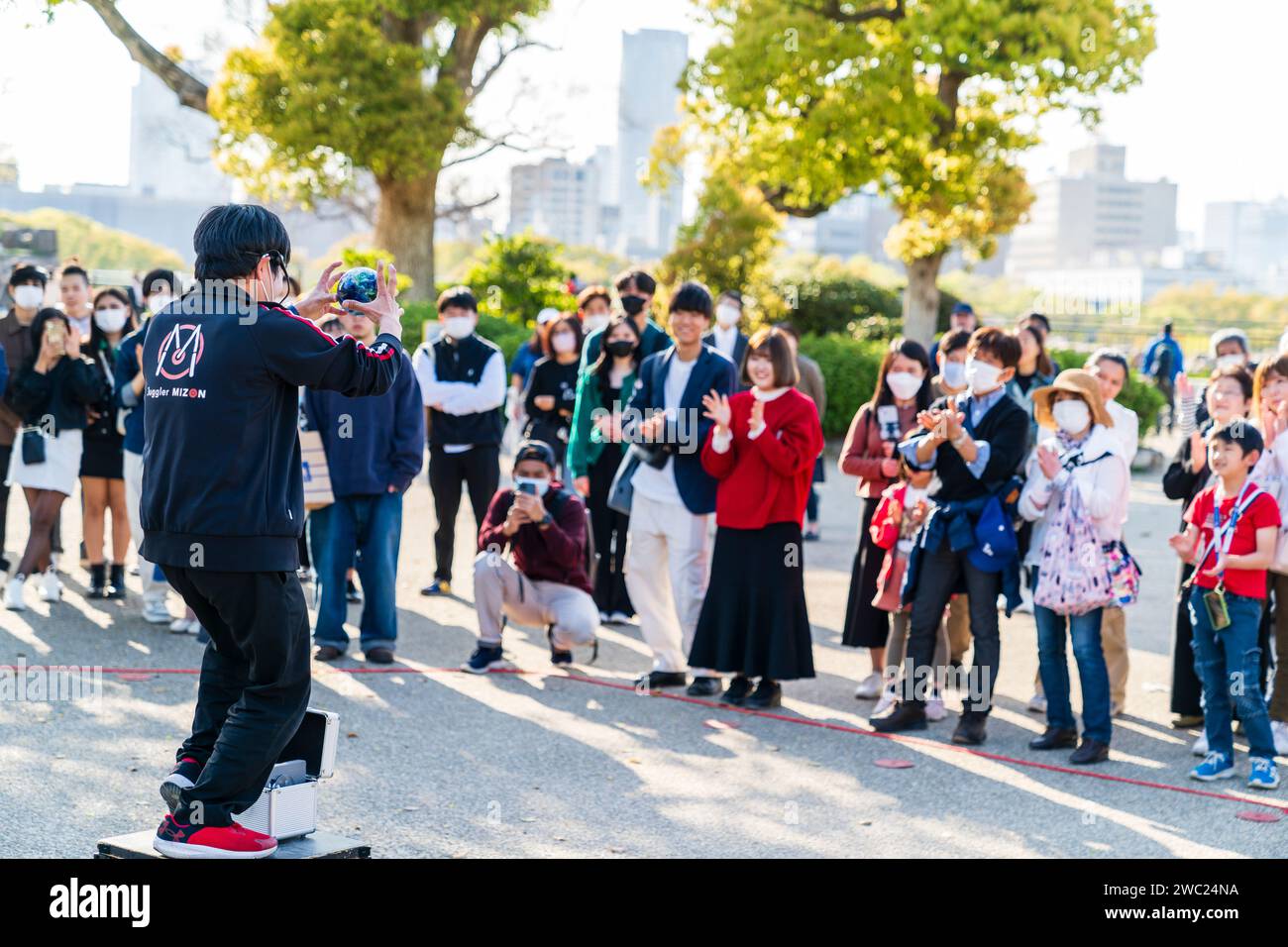Juggler standing on small table entertaining a small crowd of people ...
