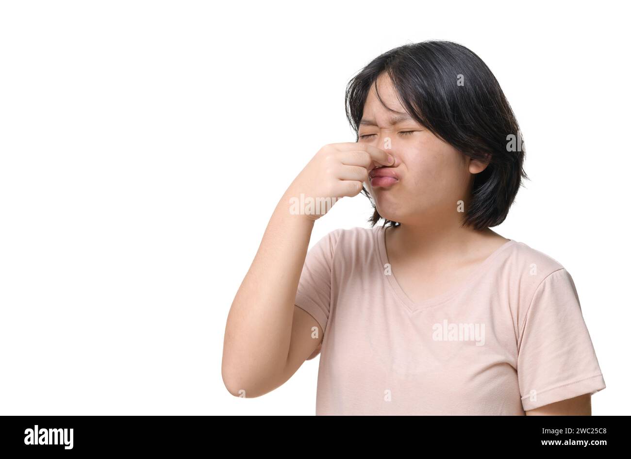 cute girl wearing a pink T-shirt covers her nose with her hand because it smells bad. white ...