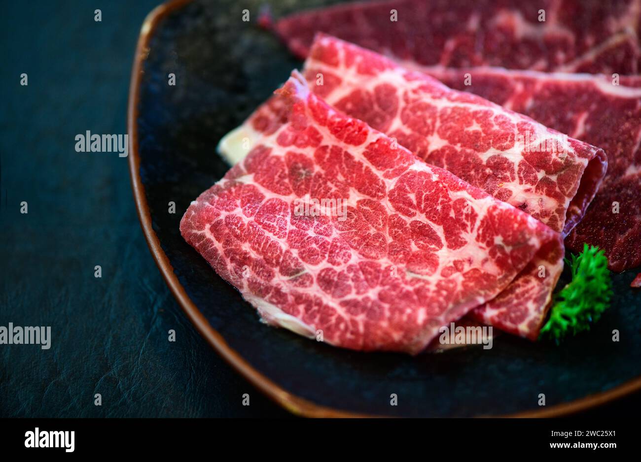 Sliced topside wagyu beef for yakiniku on plate on black background ...