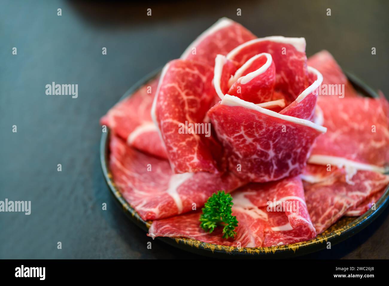 Sliced wagyu marbled beef for yakiniku on plate on black background ...
