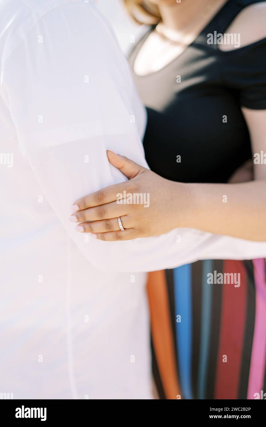 Woman put her palm on the arm of man hugging her waist. Cropped ...