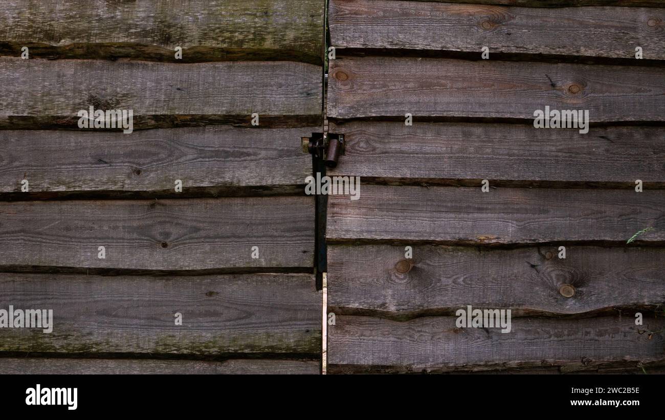 A wooden fence and a gate made of planks with a lock. Wooden board ...