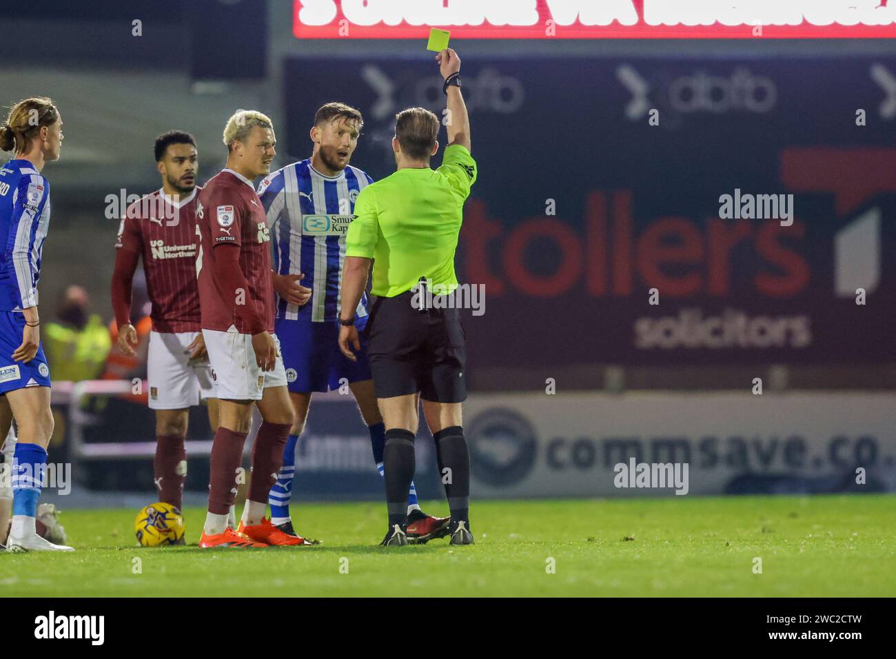 Referee Anthony Backhouse shows a yellow card to Wigan Athletic's ...
