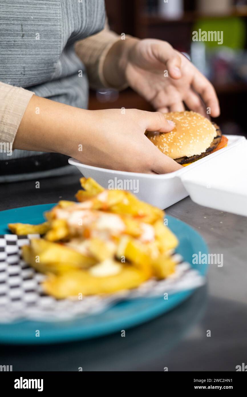 packing a hamburger and fries in a container for delivery, fast and ...