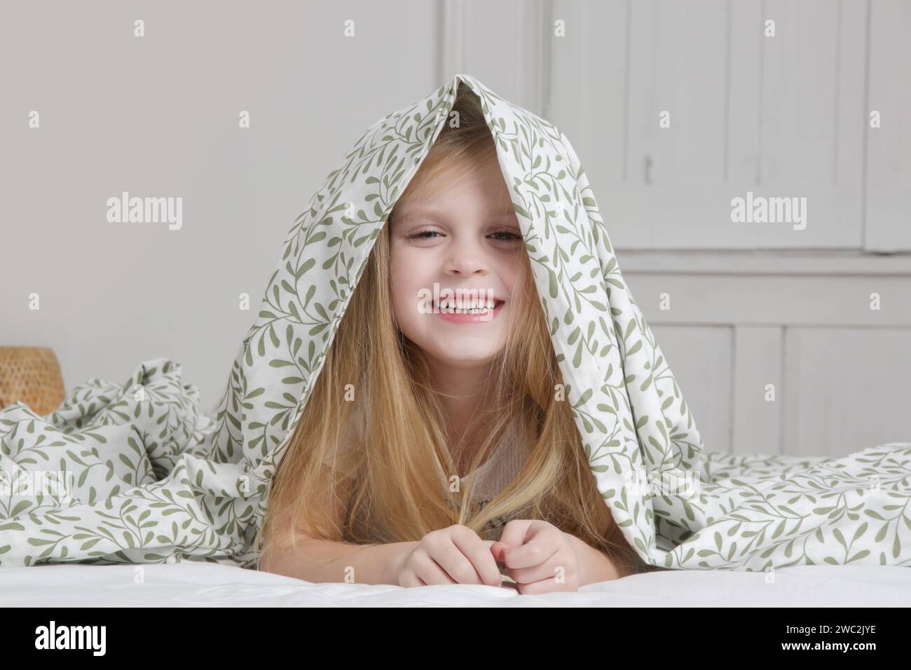 Adorable little preschool girl hiding under blanket, smilling and ...