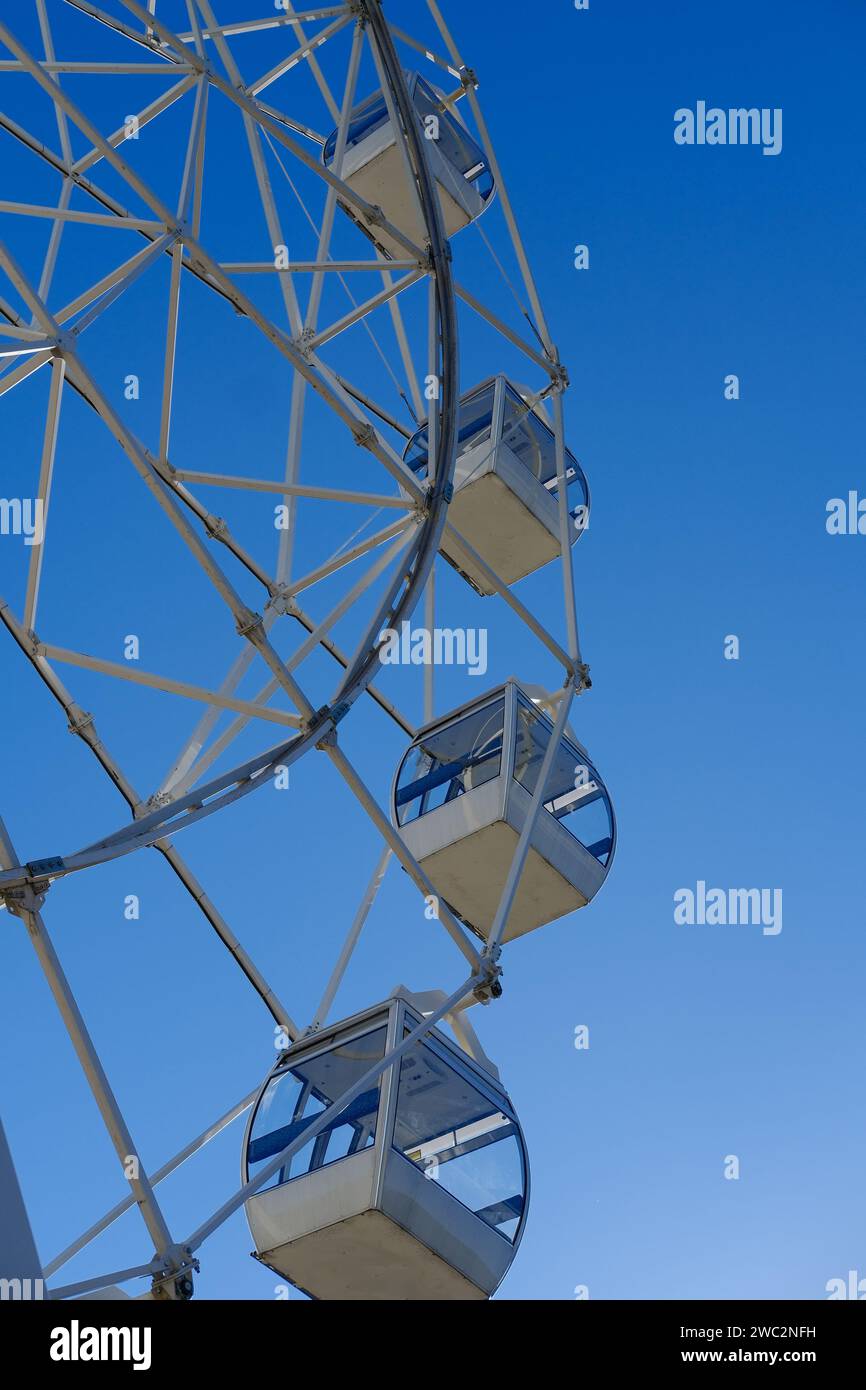 Modern ferris wheel in an amusement park against blue sky with clouds ...