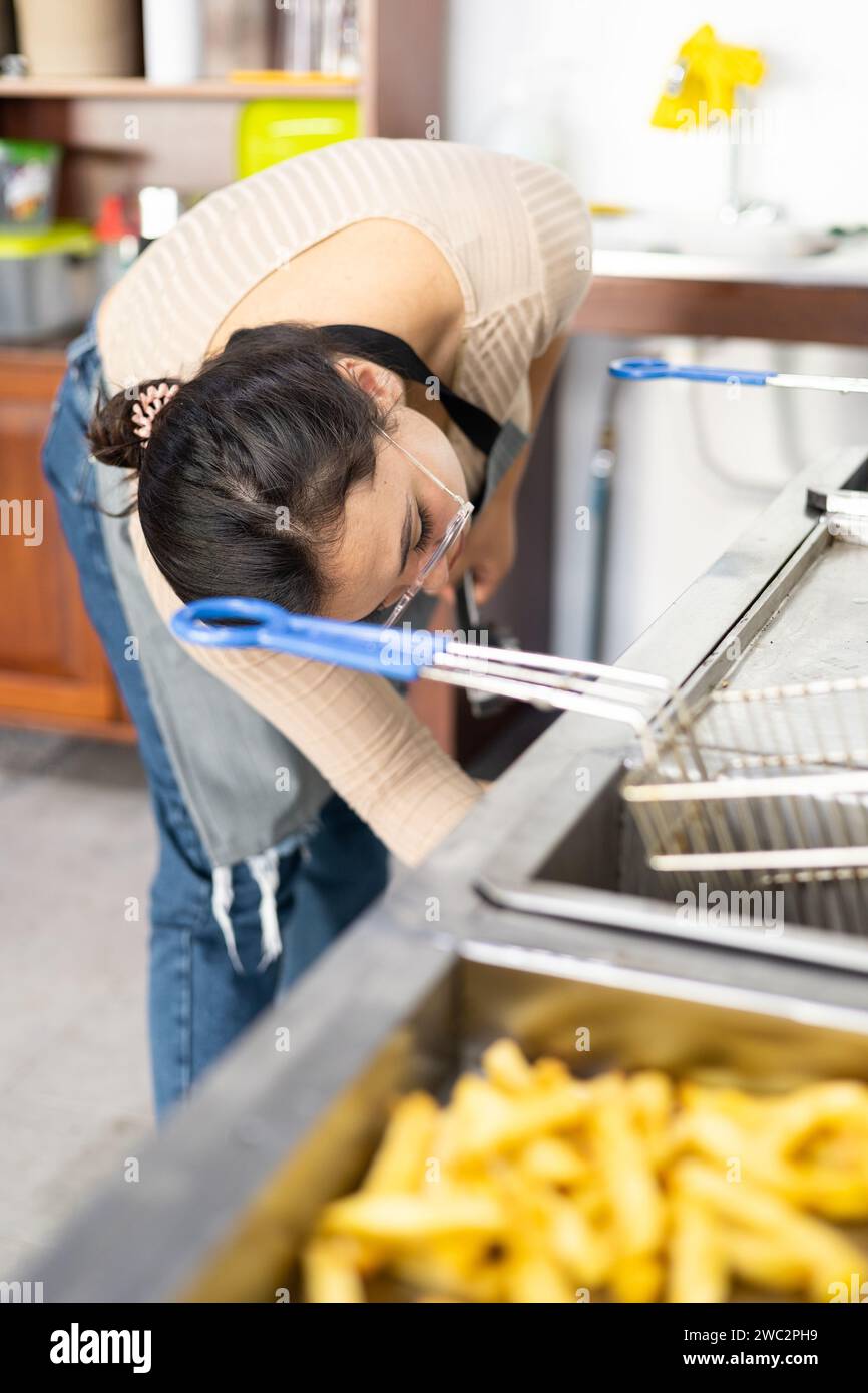 young woman working, turning on an industrial kitchen for fast food ...