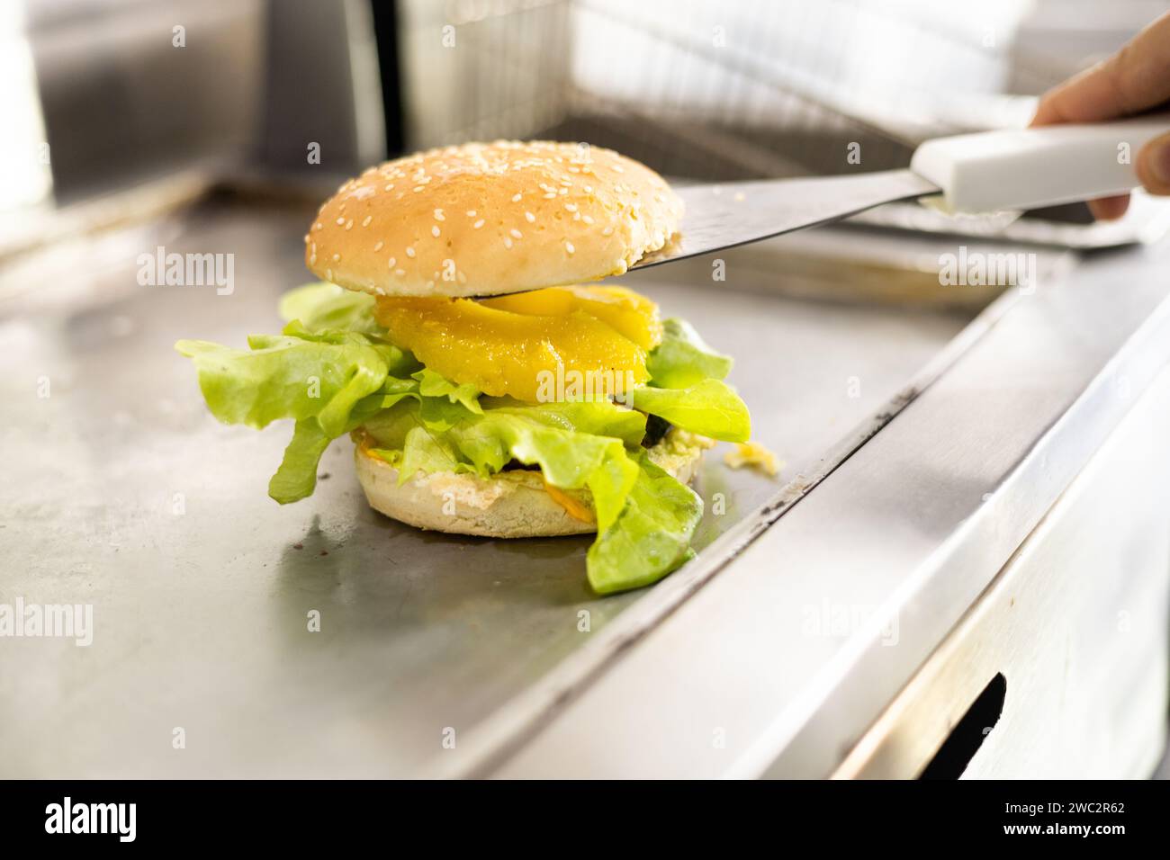 cooking, assembling a burger with bread, cheese, meat and lettuce, in ...