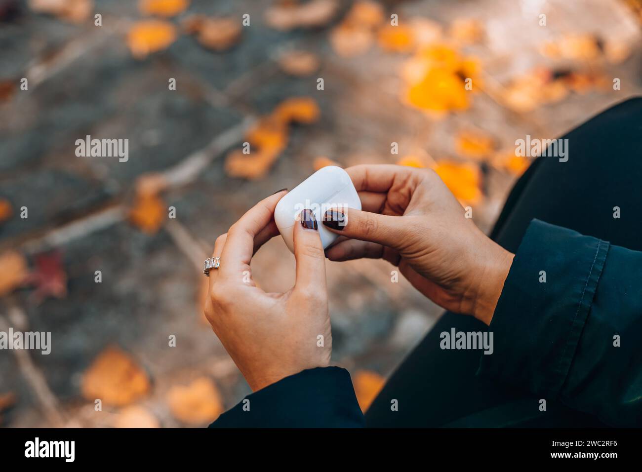 Close-up of a woman taking out a white wireless earbud from his ...