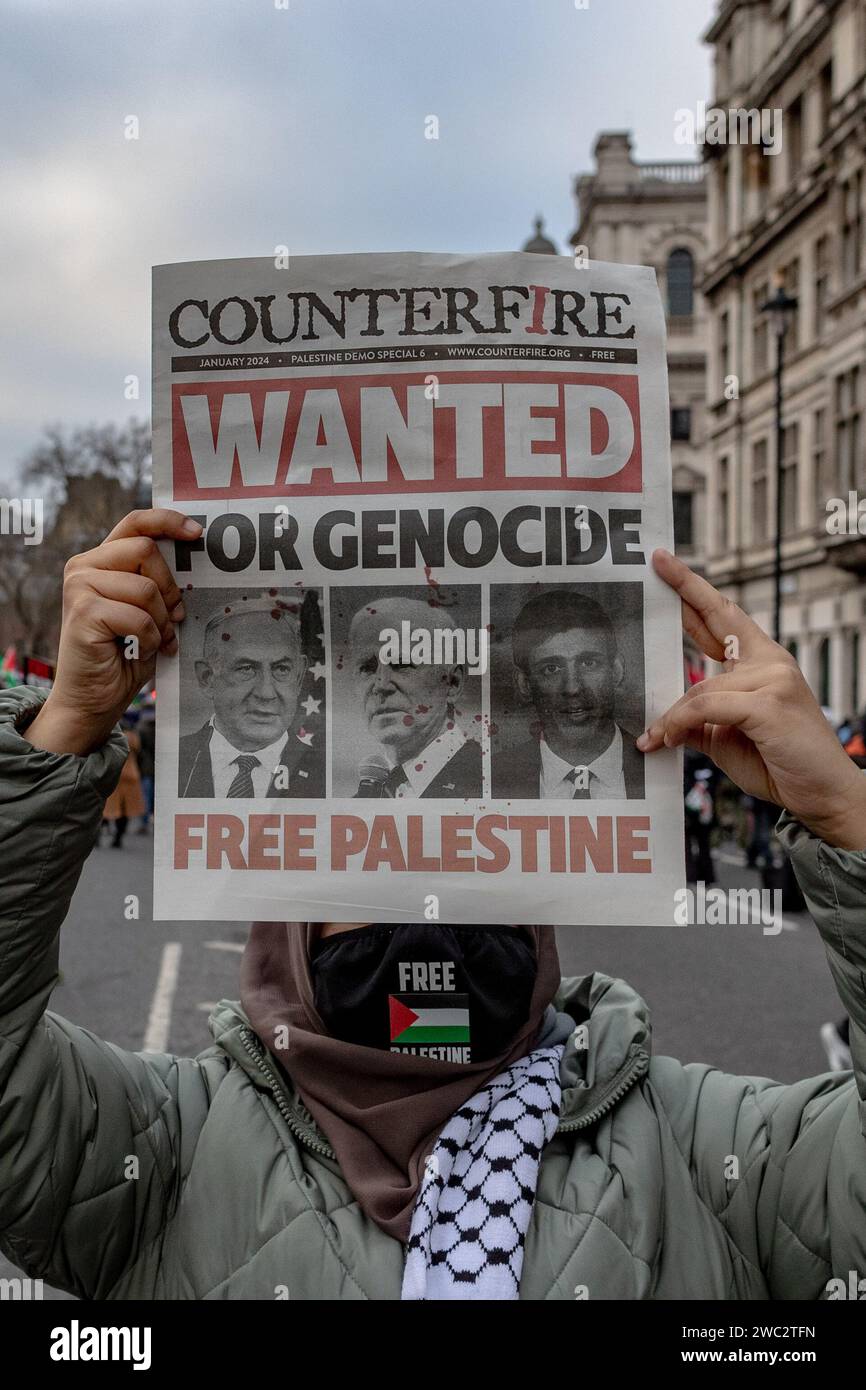 A demonstrator raises a newspaper front page labelling Israeli PM ...