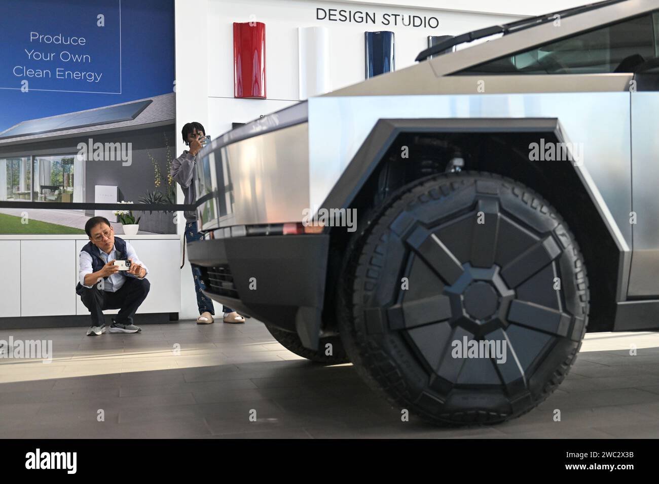 People look on at a Tesla Cybertruck on display at a Tesla dealership ...