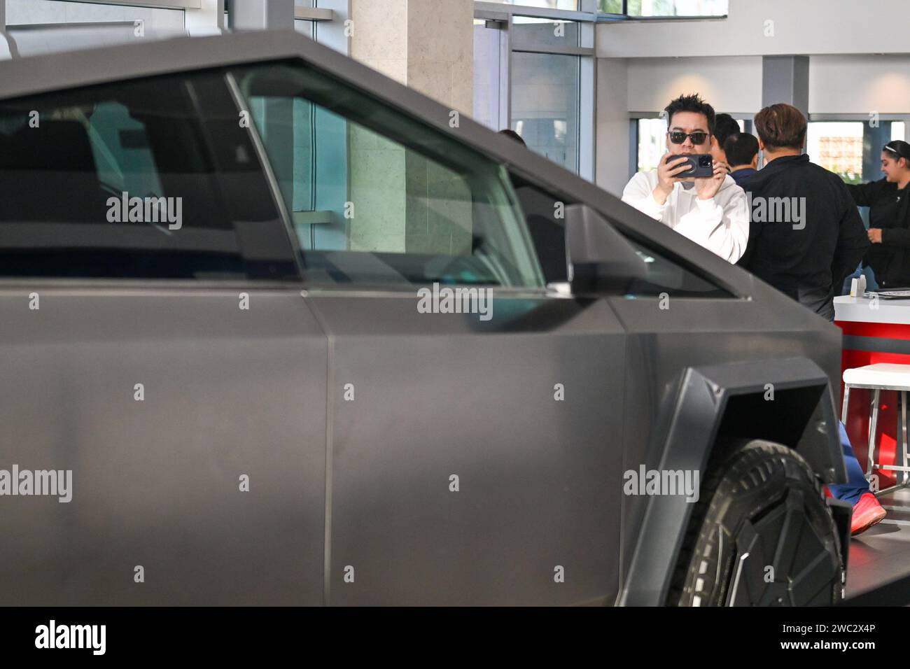People look on at a Tesla Cybertruck on display at a Tesla dealership ...