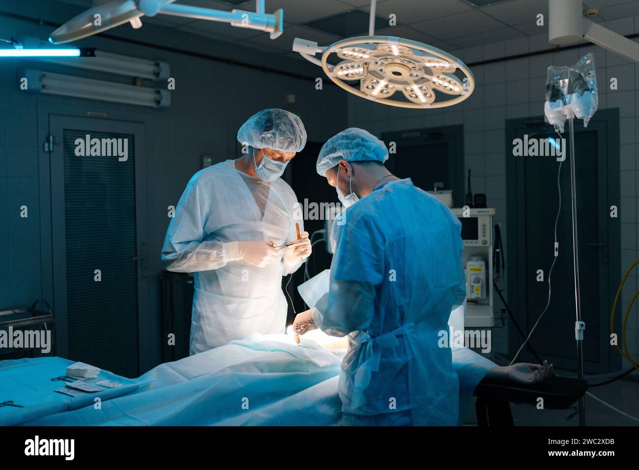Rear view of team of professional surgeons performing invasive surgery ...