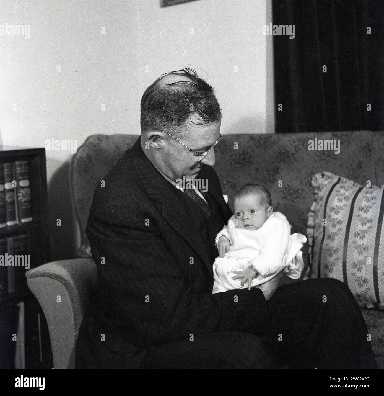 1950s, historical, holding the baby!...a gentleman in a suit & tie ...