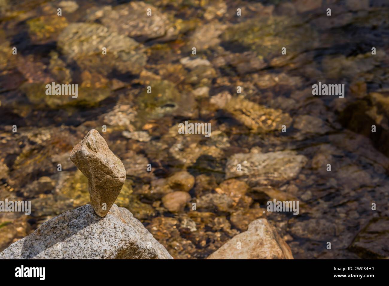 Large rock shaped like a thumb balanced on top of another larger stone ...