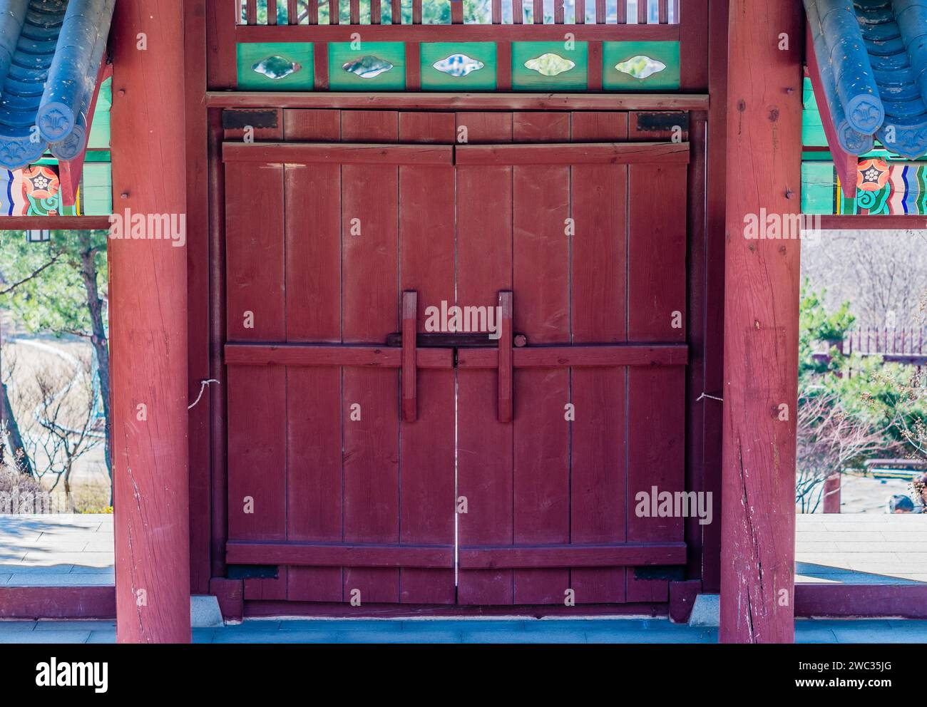 Red wooded gate with tiled roof and colorful, oriental design at a ...