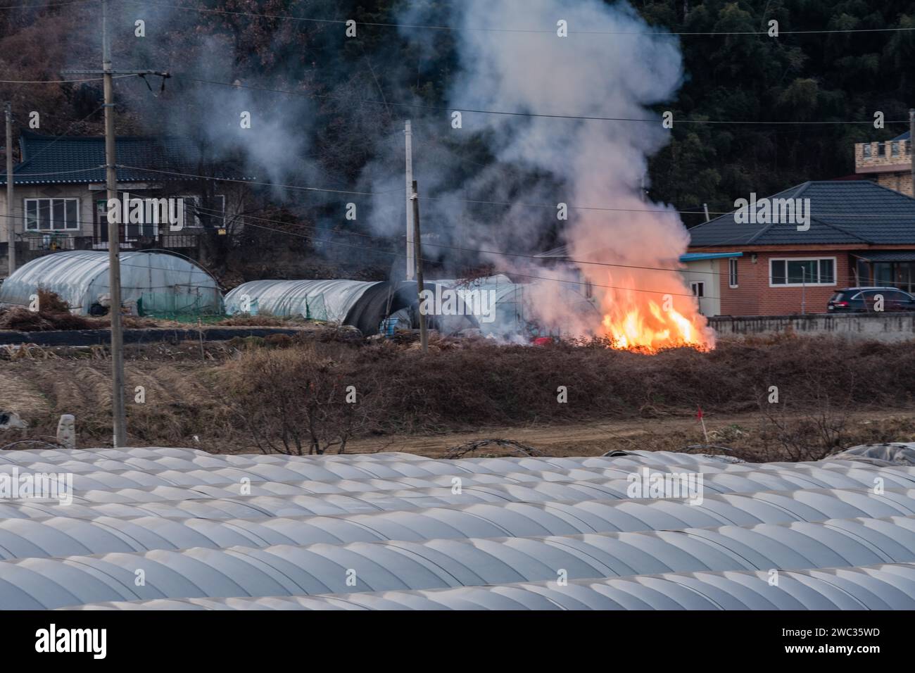 Large open fire with yellow flames and billowing smoke outside near a ...